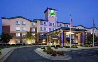 Um hotel Holiday Inn Express com entrada coberta, bandeira e estacionamento.