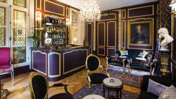 Uma área de bar luxuosa com balcão, assentos e um candelabro.