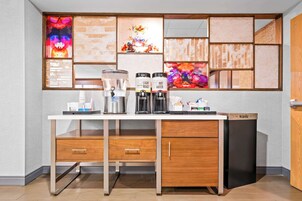 Cozinha moderna com estação de café embutida, lixeira e parede decorativa com obras de arte.