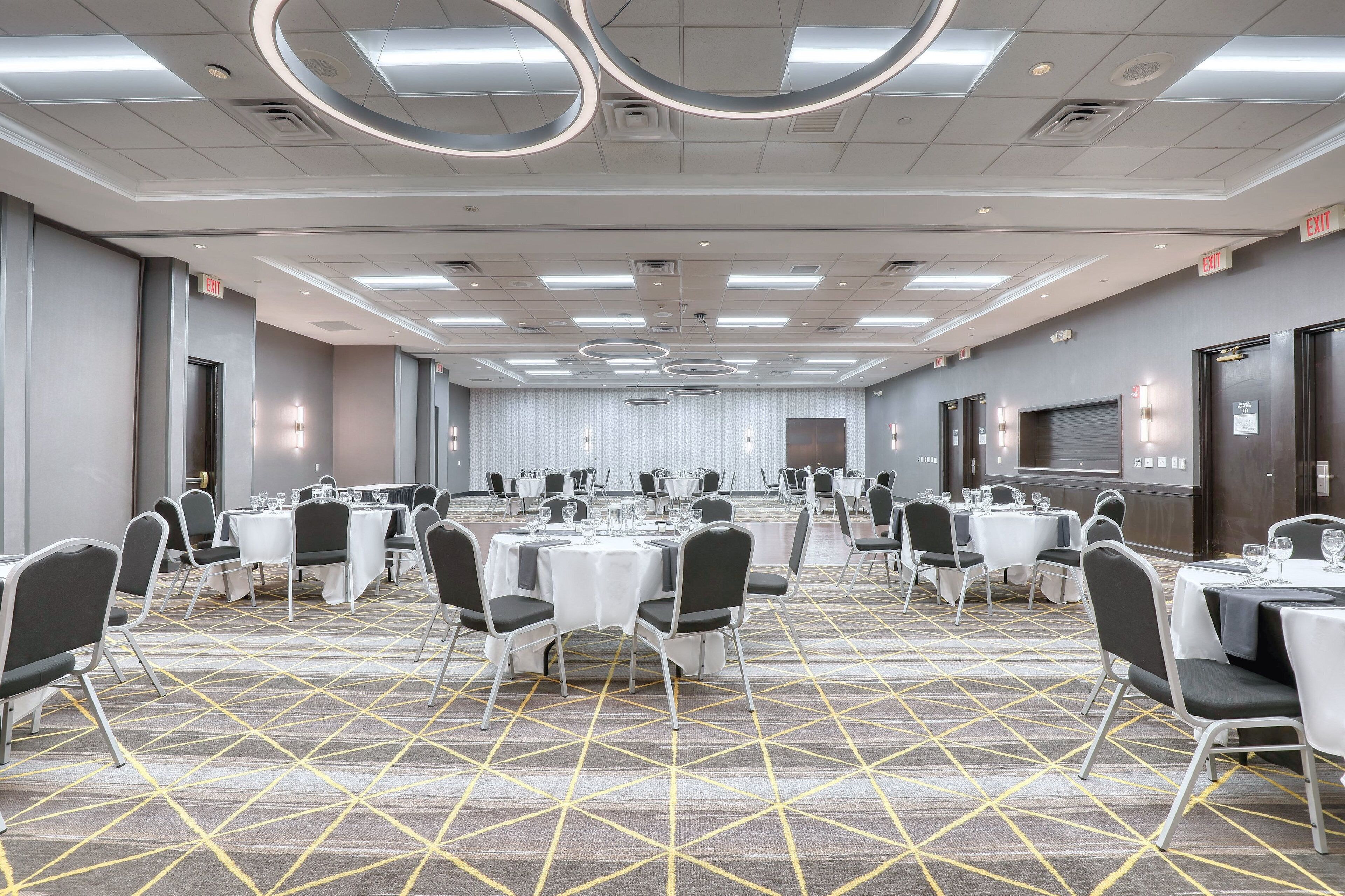 Sala de conferência com várias mesas e cadeiras, equipada com placas de identificação e copos d'água.