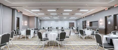 Sala de conferência com várias mesas e cadeiras, equipada com placas de identificação e copos d'água.