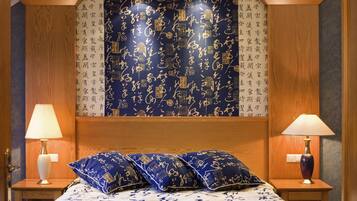Quarto com cama, duas luminárias de cabeceira, painel de cabeceira de madeira e parede com caligrafia.