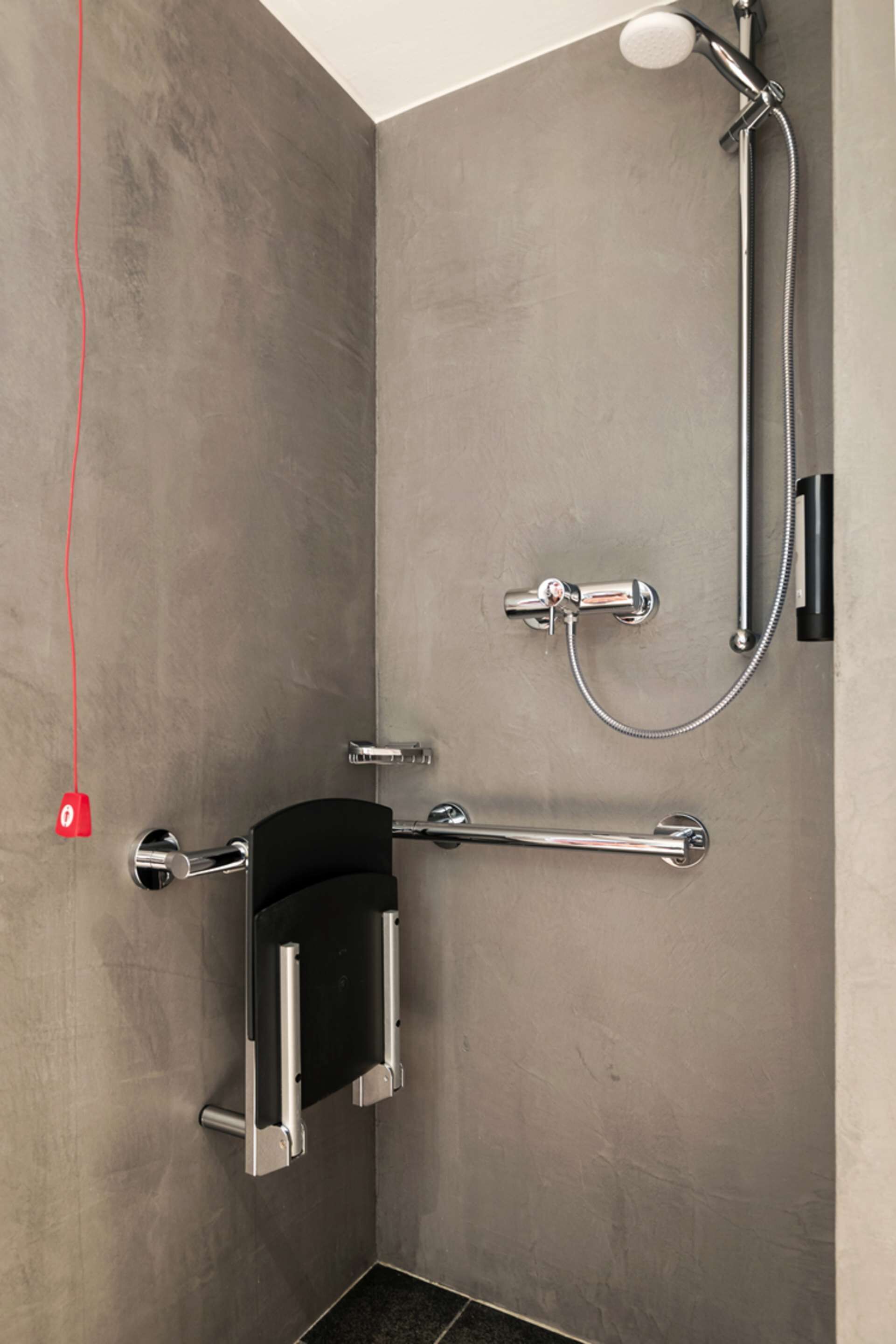 Uma área de chuveiro moderna com chuveiro manual, acessório de mão e torneira fixada na parede.