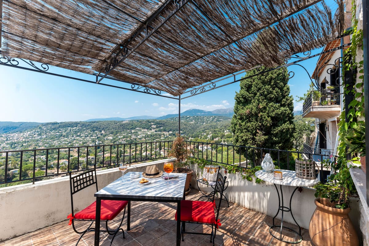 Terraço com mesa e cadeiras, vista da cidade e planta em vaso.