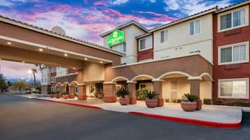Um hotel com uma placa indicando 'La Quinta Inn & Suites', com design moderno, teto plano e várias janelas.