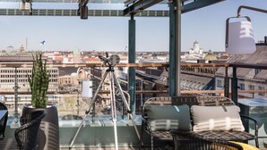 Terraço no telhado com um telescópio, área de estar e um vaso de planta.
