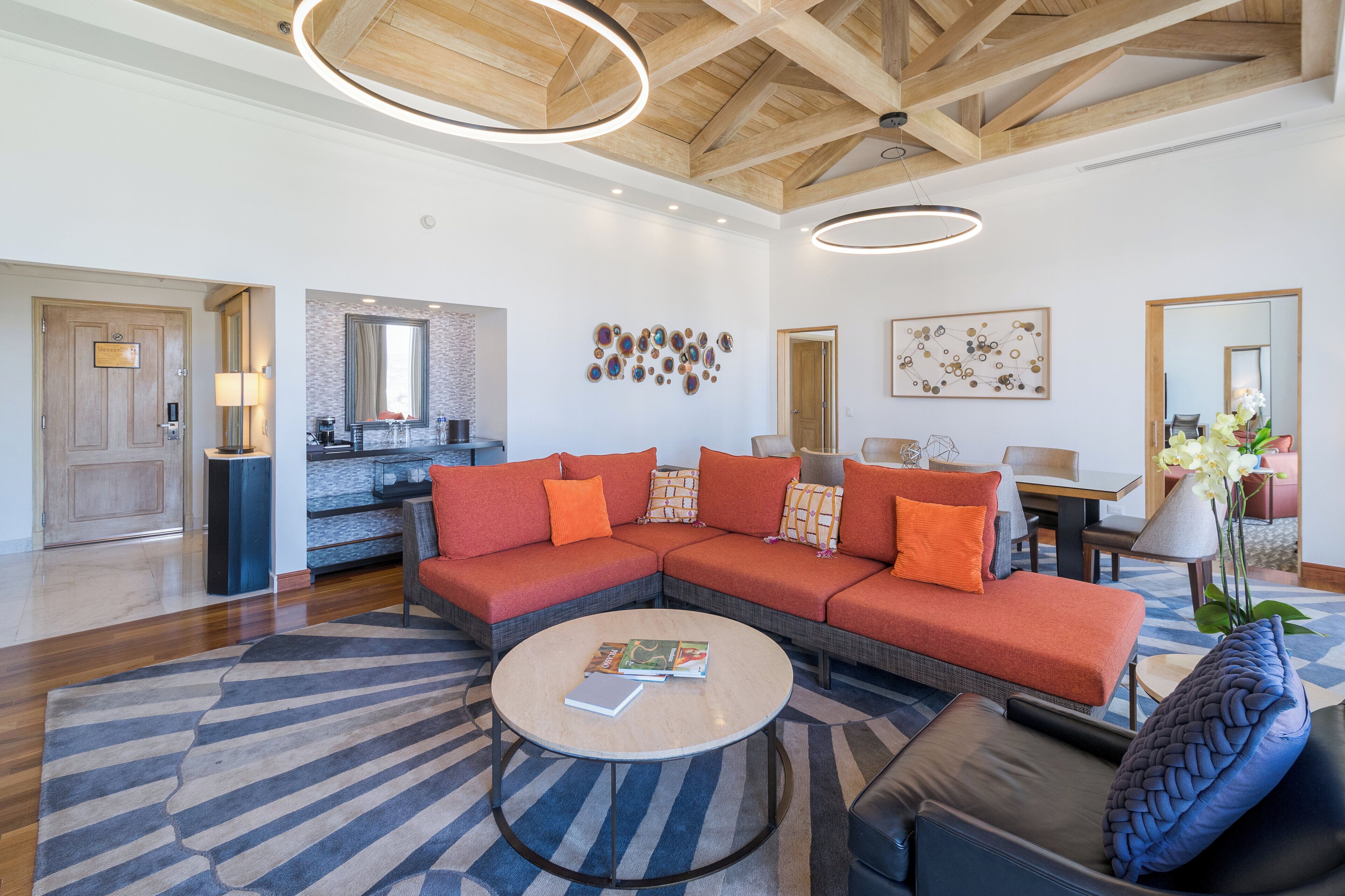 Uma sala de estar moderna com um sofá seccional, uma mesa de centro redonda e um espaço de jantar com mesa e cadeiras.