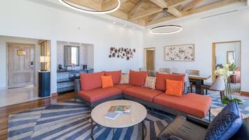 Uma sala de estar moderna com um sofá seccional, uma mesa de centro redonda e um espaço de jantar com mesa e cadeiras.