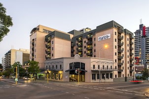 Um hotel de vários andares com design arquitetônico moderno, com varandas e uma entrada imponente.