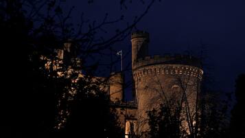 Um castelo histórico com uma torre imponente, rodeado por árvores.