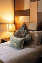 Uma cama bem arrumada com duas almofadas decorativas e um abajur.