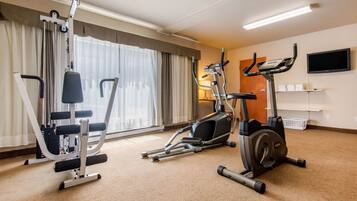 Quarto de hotel com bicicleta ergométrica, esteira e aparelho de musculação.