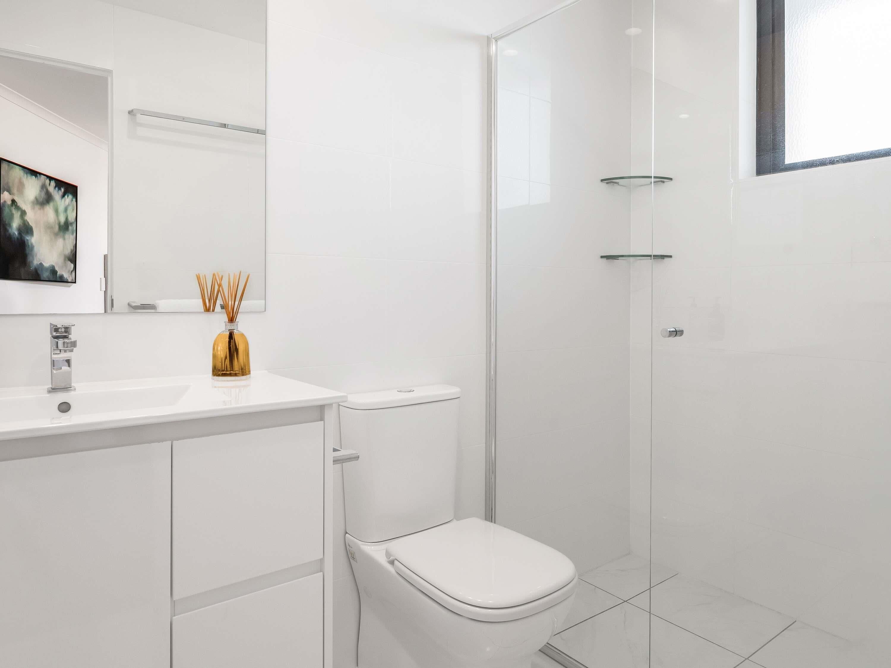 Casa de banho moderna com lavatório branco, sanita e cabine de duche em vidro.