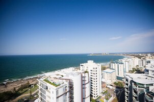 Paisagem costeira com edifícios modernos, uma praia e o oceano.