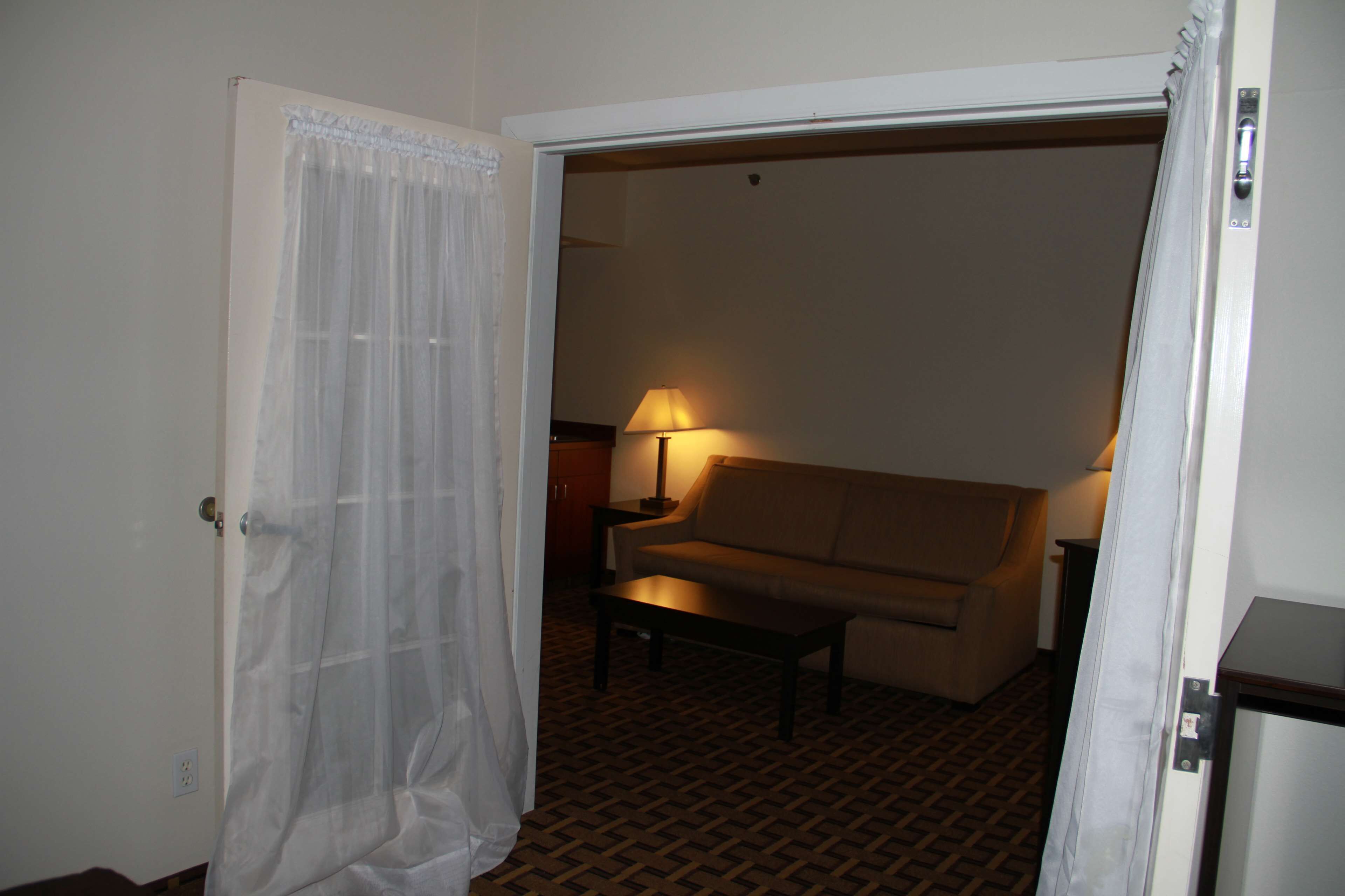Um quarto com carpete estampado, um sofá, uma mesa de centro e um abajur.