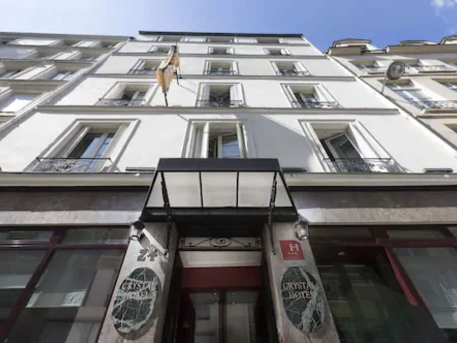 Um edifício com vários andares, grandes janelas e uma placa indicando que é um hotel.