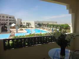 Uma área de piscina com vista desobstruída, cadeiras de descanso e um edifício com arcos ao fundo.