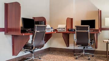 Uma sala de conferências com duas mesas, cada uma com um computador, impressora e cadeira.