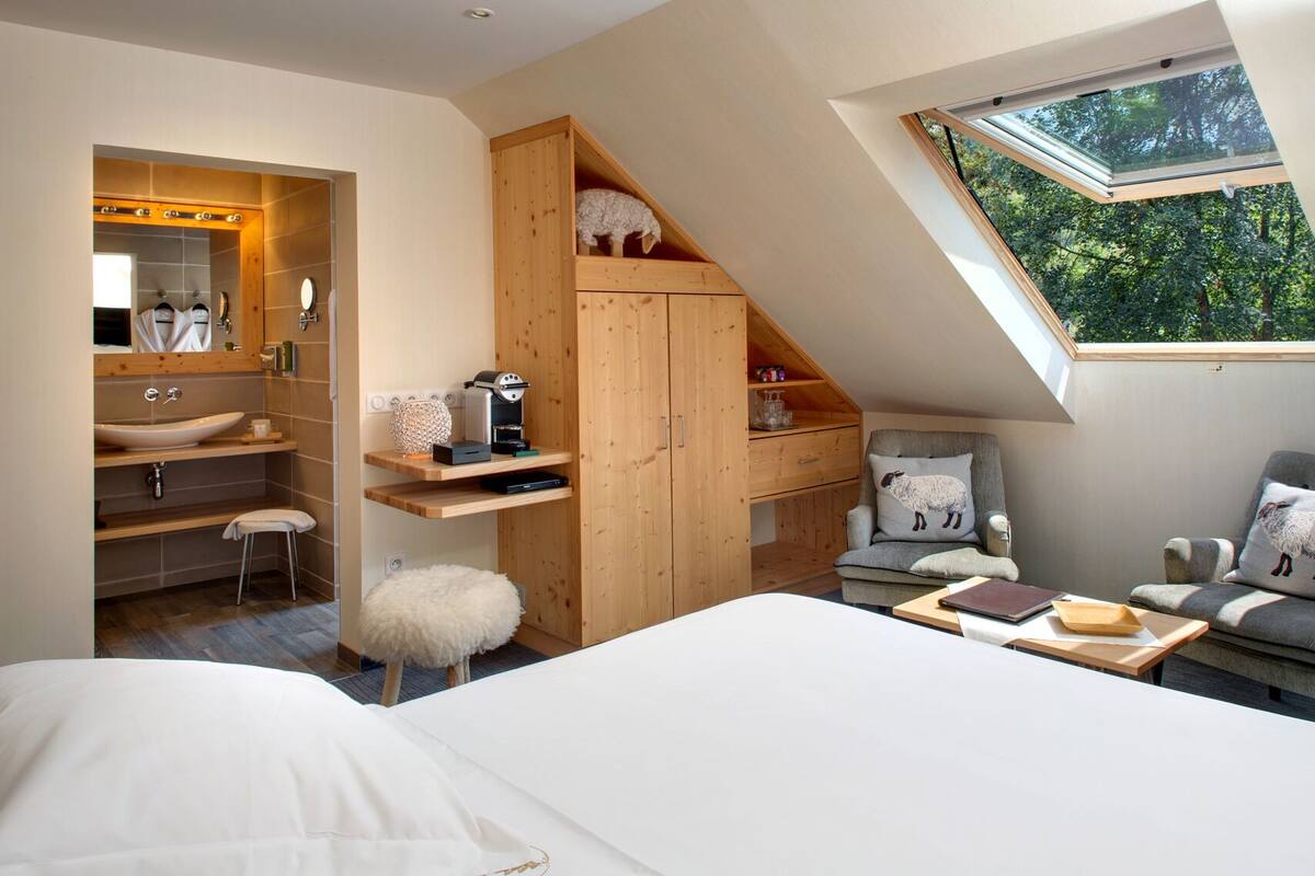 Um quarto com claraboia, estantes de madeira, um sofá e uma cama.