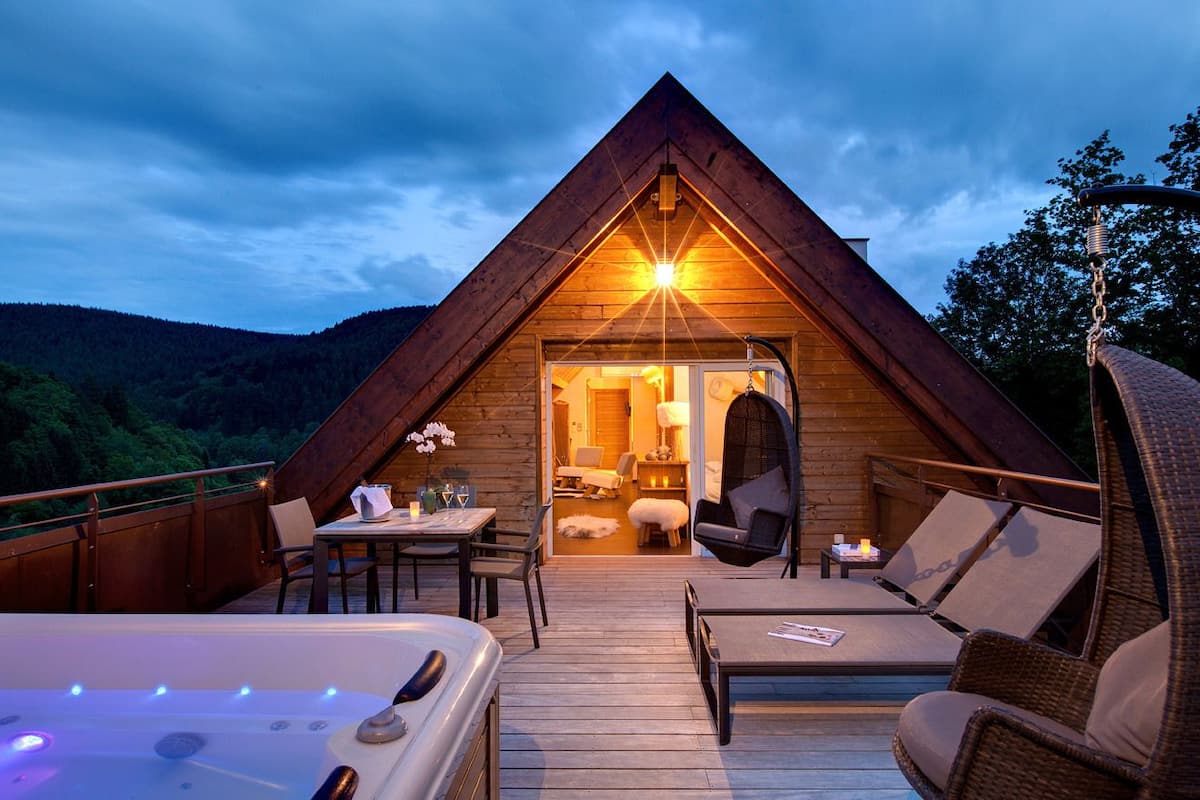 Uma cabana de madeira com hidromassagem, área de estar externa e interior acolhedor.