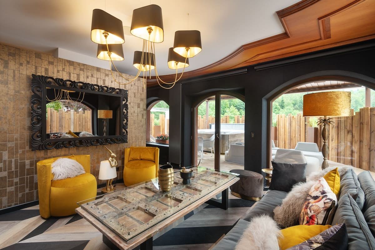 Uma sala de estar moderna com lareira, poltronas amarelas, um sofá e uma mesa de centro de vidro.