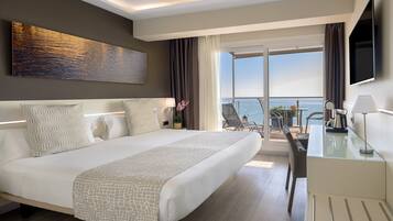 Quarto de hotel moderno com uma cama grande, uma escrivaninha e vista para o oceano.