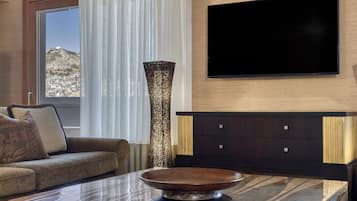 Uma sala de estar moderna com um sofá, uma mesa de centro com uma tigela decorativa, um vaso alto e uma televisão de tela plana fixada na parede.