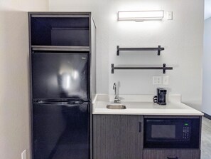 Um frigorífico, um micro-ondas, uma cafeteira/bule, uma torradeira 