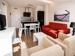 Uma sala de estar moderna com um sofá vermelho, cadeiras brancas e uma televisão.