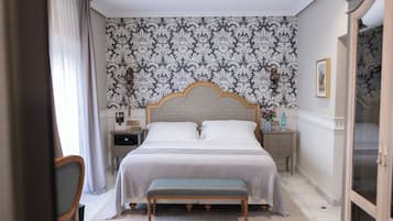 Um quarto bem arrumado com uma cama grande, mesas de cabeceira, um banquinho e um guarda-roupa.