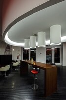 Interior moderno com teto curvo, área de bar em madeira e banquetas brancas.