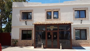 Um hotel com fachada branca, várias janelas e entrada coberta de azulejos.