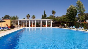 Piscina com espreguiçadeiras e área de estar coberta.