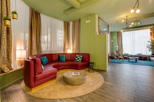 Uma sala de estar moderna com um sofá seccional vermelho, uma mesa de centro redonda e piso estampado.