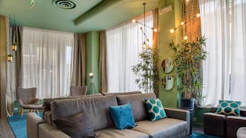 Sala de estar com sofá, cadeiras, mesa de centro e uma grande planta em vaso.
