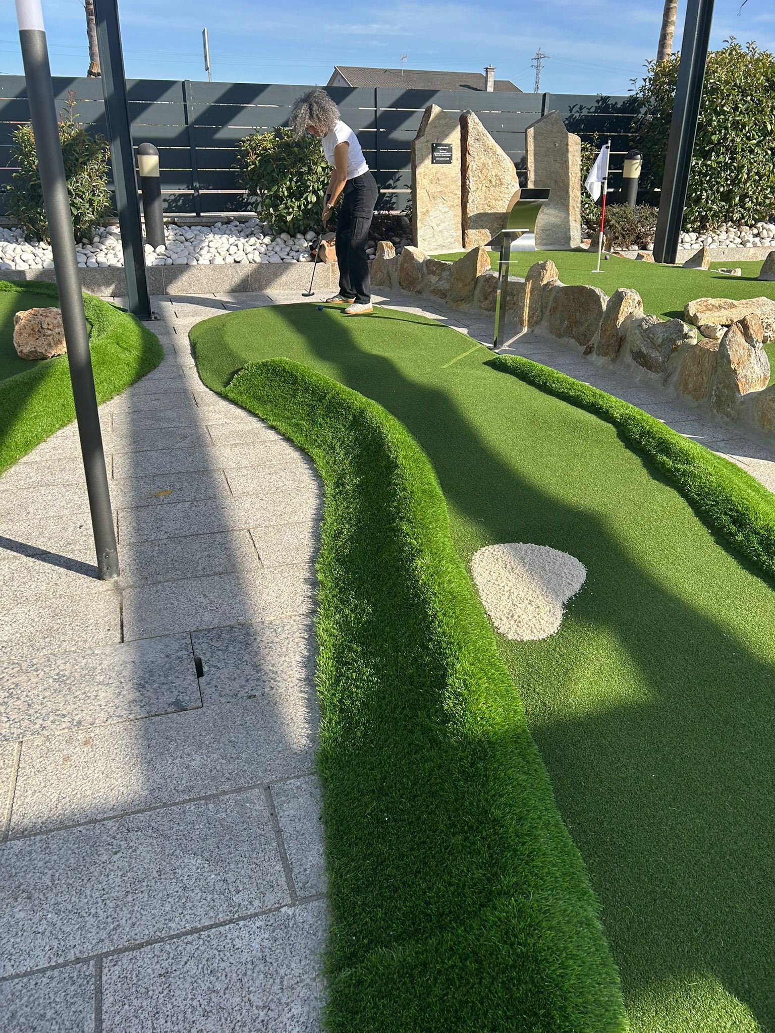 Um putting green de golfe com um muro de pedra e haste de sinalização.