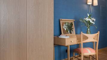 Quarto com parede de painel de madeira, parede azul de destaque, escrivaninha de madeira com cadeira, um vaso com flores e duas luminárias fixadas na parede.