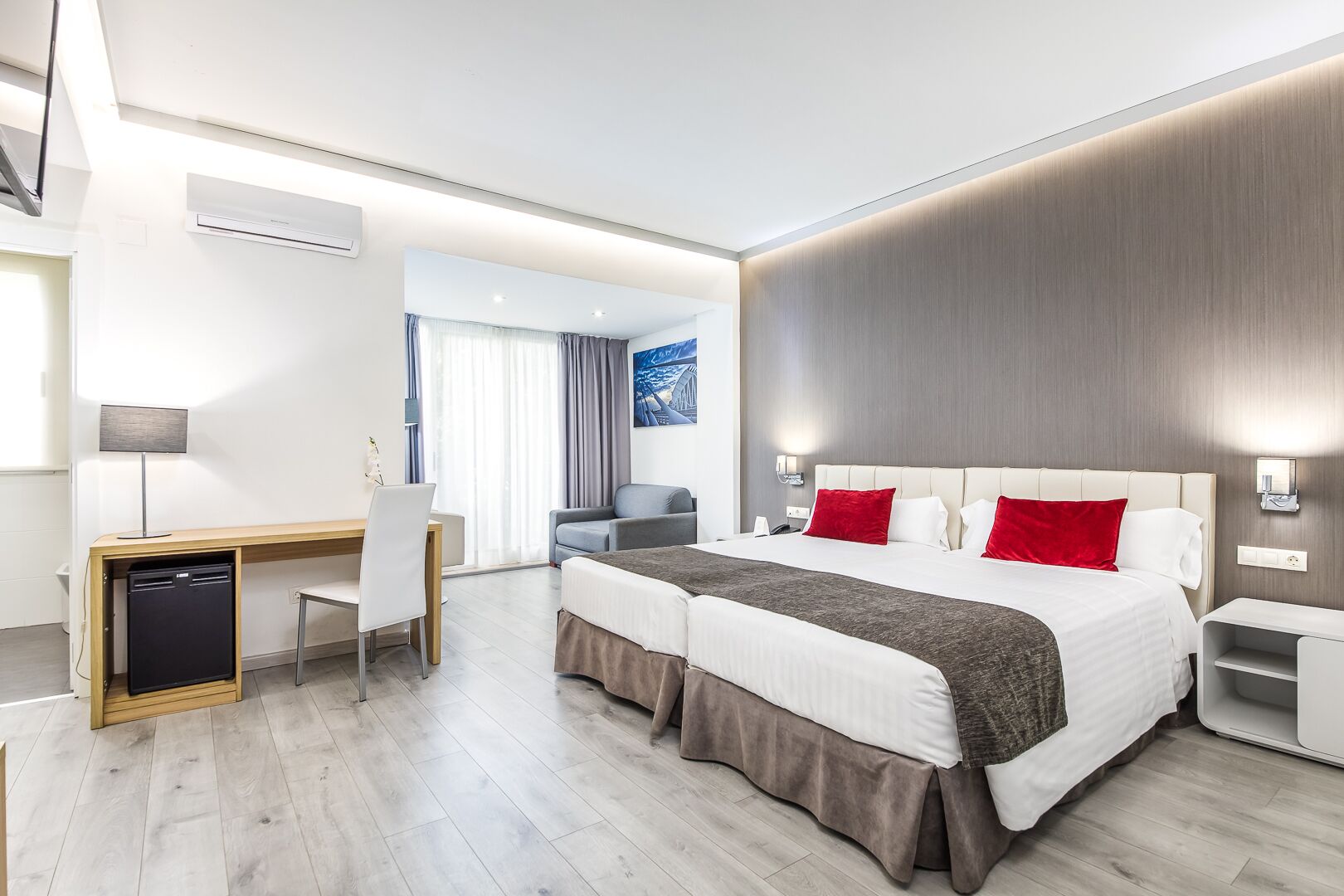 Quarto de hotel moderno com uma cama grande, uma escrivaninha e uma cadeira.