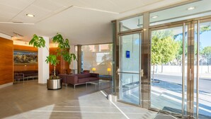 Um hall moderno com balcão de recepção, área de estar e grandes portas de vidro que dão para o exterior.