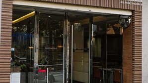 Entrada de restaurante com portas de vidro, fachada de madeira e placa indicando 