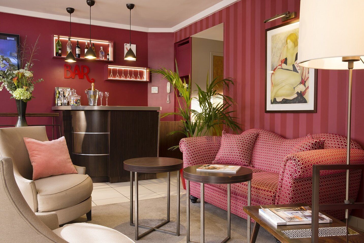 Uma sala de estar moderna com parede listrada em vermelho, um sofá, uma poltrona, uma mesa de centro, um espaço de bar com garrafas e copos, e um quadro grande.