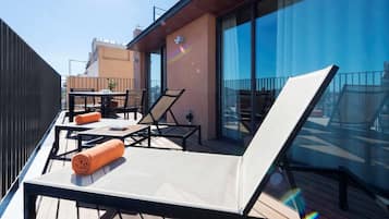 Terraço no telhado com espreguiçadeiras, uma mesa e cadeiras.