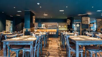 Um restaurante com várias mesas e cadeiras, um espaço de bar e um balcão com o cardápio.