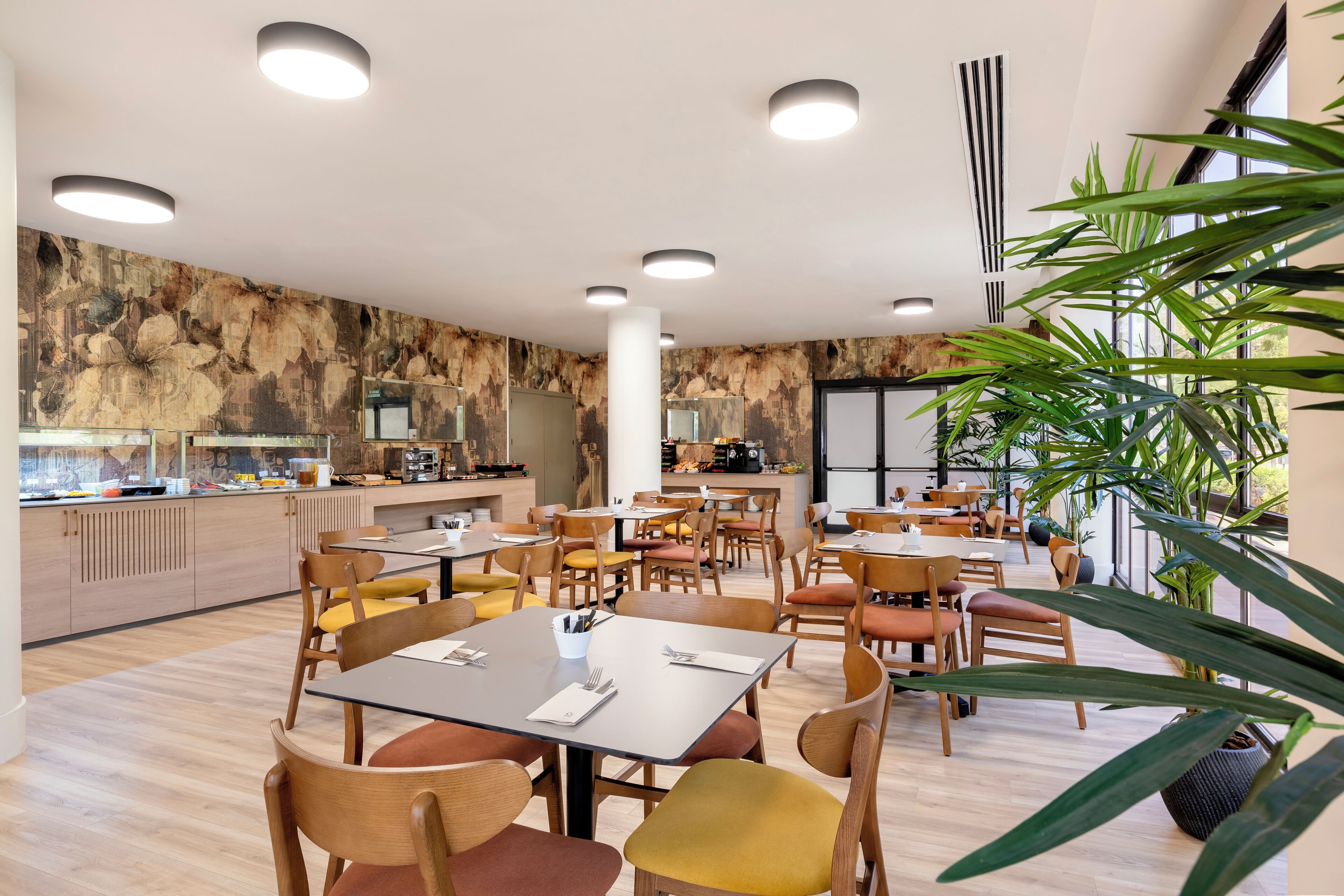 Um restaurante moderno com mobiliário de madeira, uma área de bar central e grandes janelas que permitem entrada de luz natural.