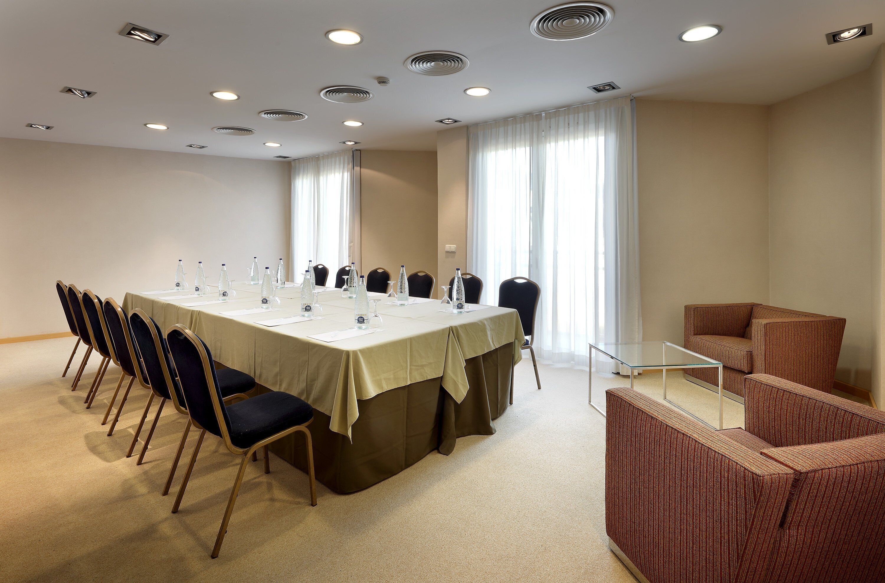 Uma sala de conferências com uma mesa comprida, cadeiras e uma mesa de centro de vidro.