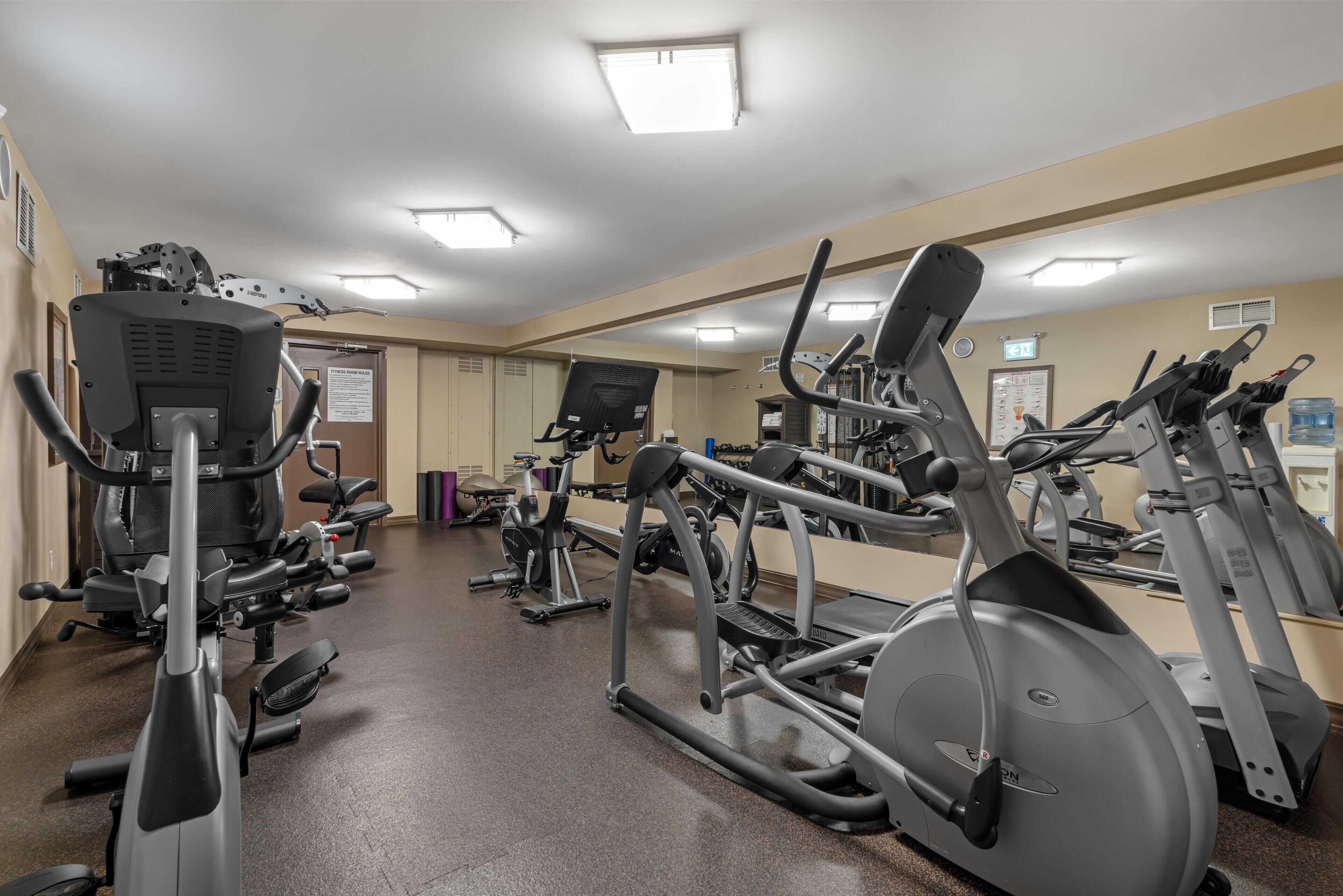 Uma academia com diversos equipamentos de exercício, incluindo esteiras, elípticos e bicicletas ergométricas.