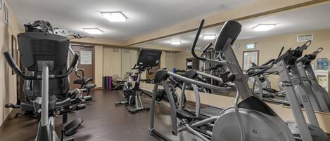 Uma academia com diversos equipamentos de exercício, incluindo esteiras, elípticos e bicicletas ergométricas.