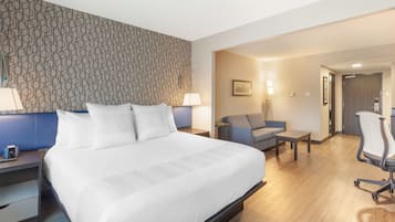 Quarto de hotel com uma cama grande, uma escrivaninha, uma cadeira e um sofá.