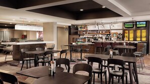 Um restaurante moderno com área de bar, diversas opções de assento incluindo mesas redondas e cadeiras, e o logotipo da Starbucks visível.