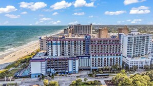 Um hotel com vários andares, área de piscina e vista para a praia.